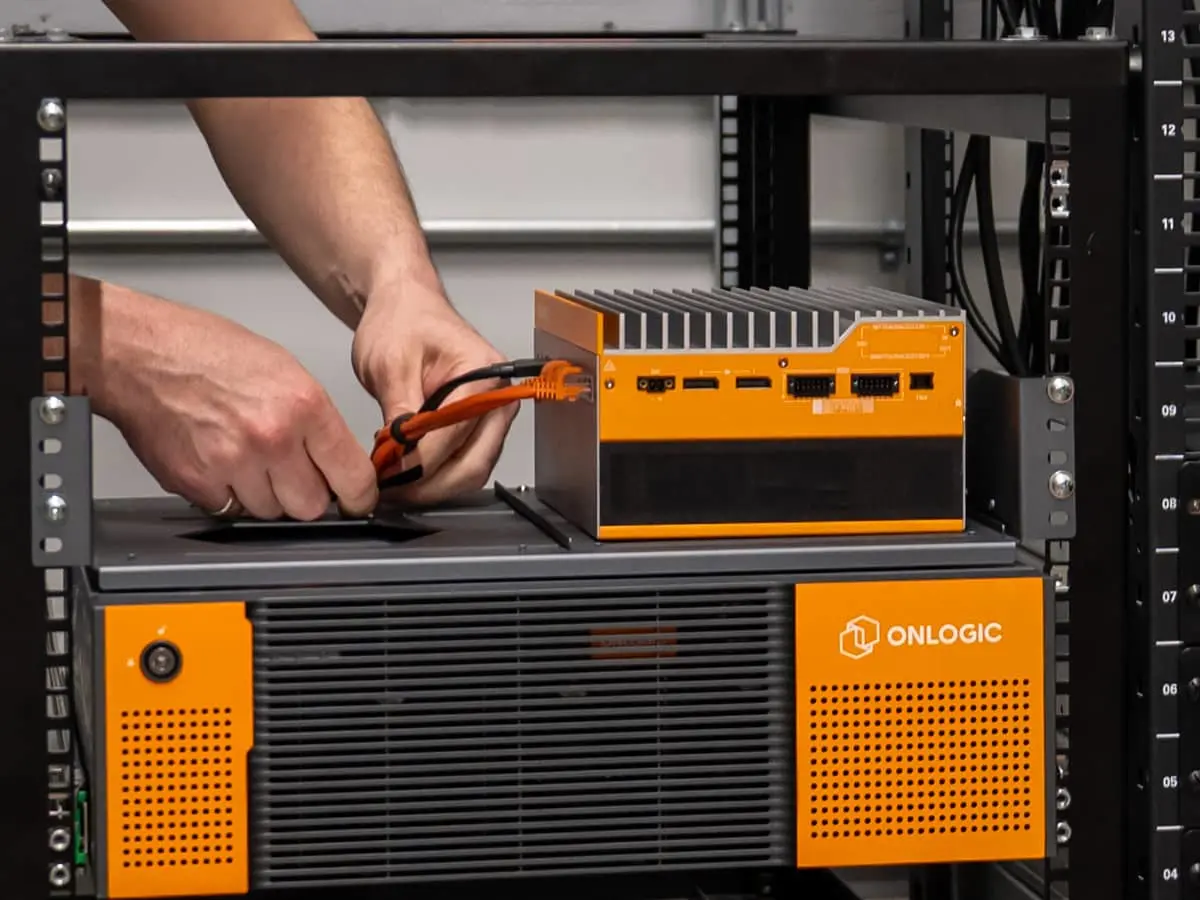 Someone plugging in wires to an OnLogic Helix 520 Series system on top of an OnLogic Axial AX300 ...