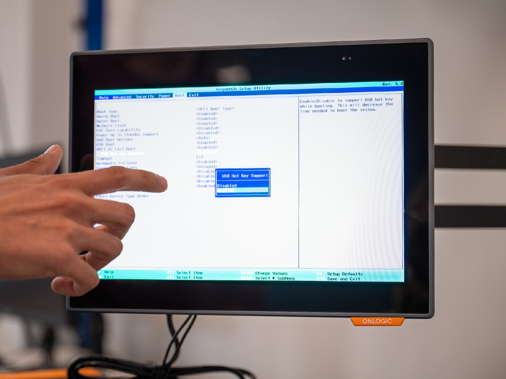 A hand touching a panel PC on which the BIOS/UEFI screen is displayed