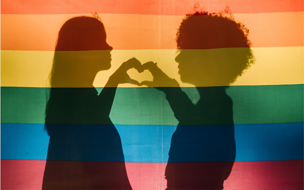 A photo of two people creating a heart with their hands in front of a ...