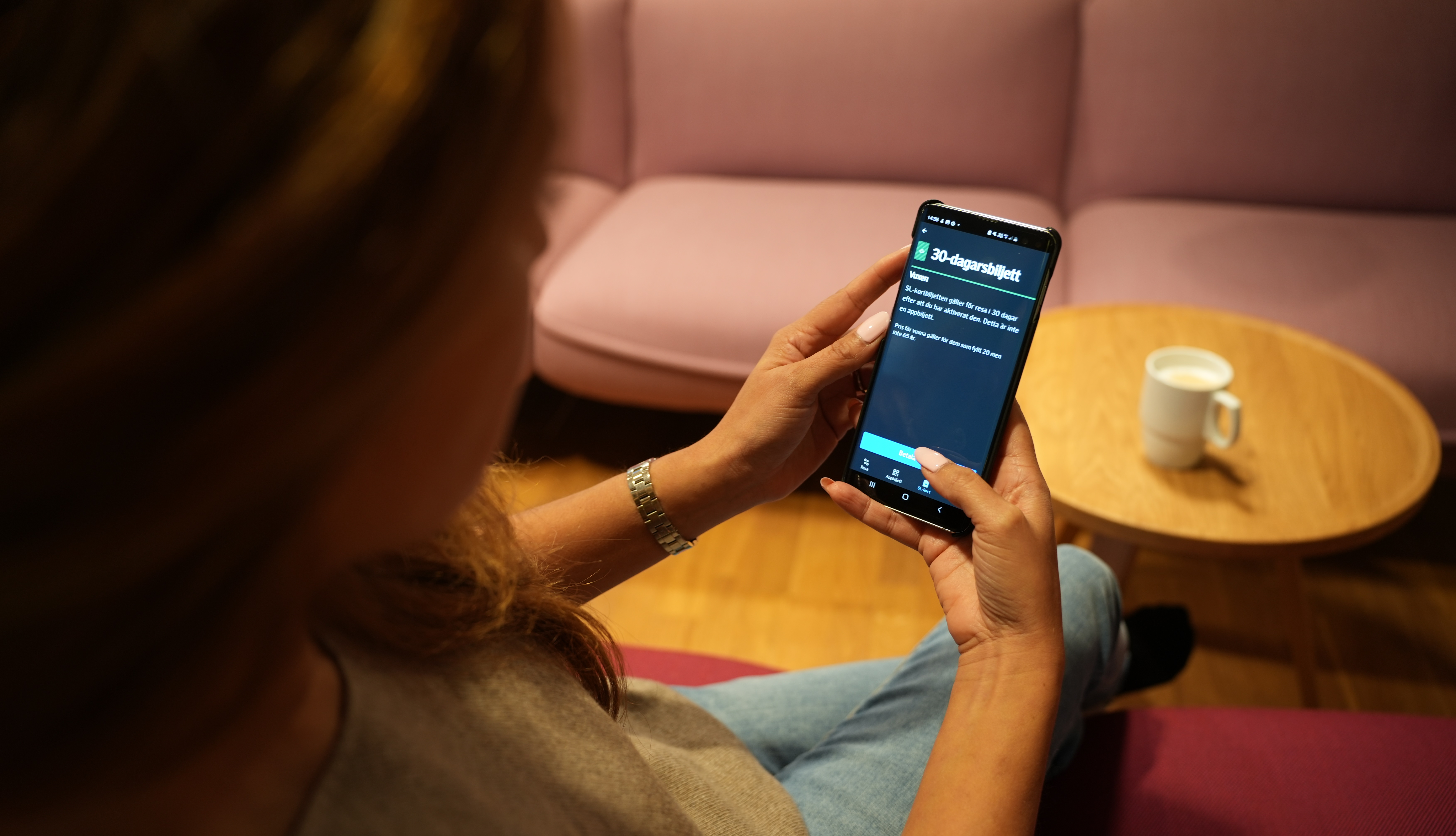 Kvinna som håller i en mobil och håller på att köpa en 30-dagarsbiljett ...