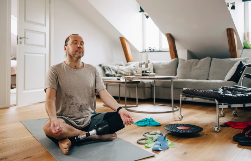 A man sitting on an exercise mat inside while meditating