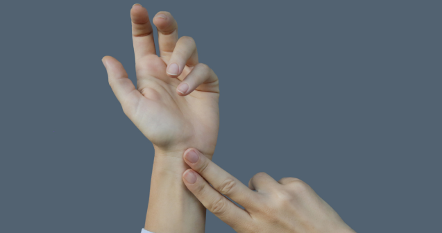 Woman holding 2 fingers on pulse checking her heart rate at home
