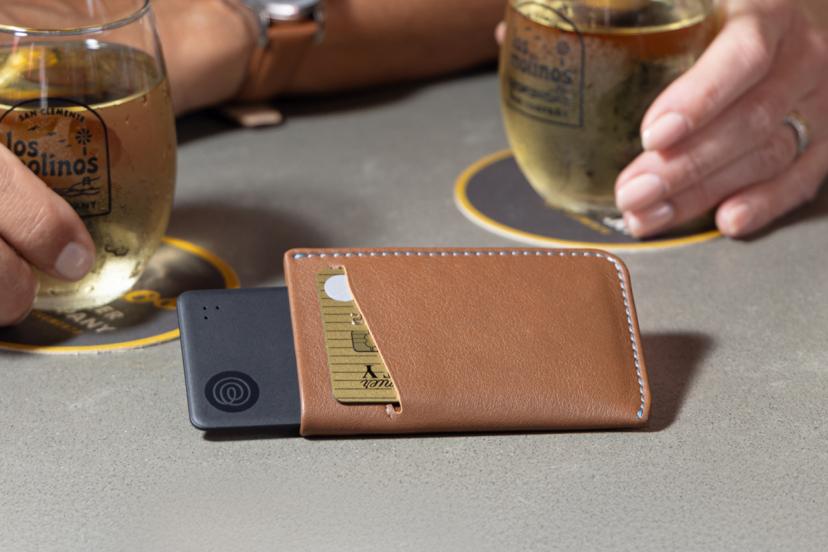 A Tile Slim Black being placed inside of a person's wallet.