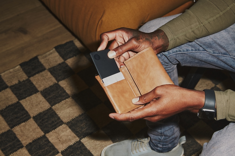 A person placing their Black Tile 2022 Slim inside their wallet.
