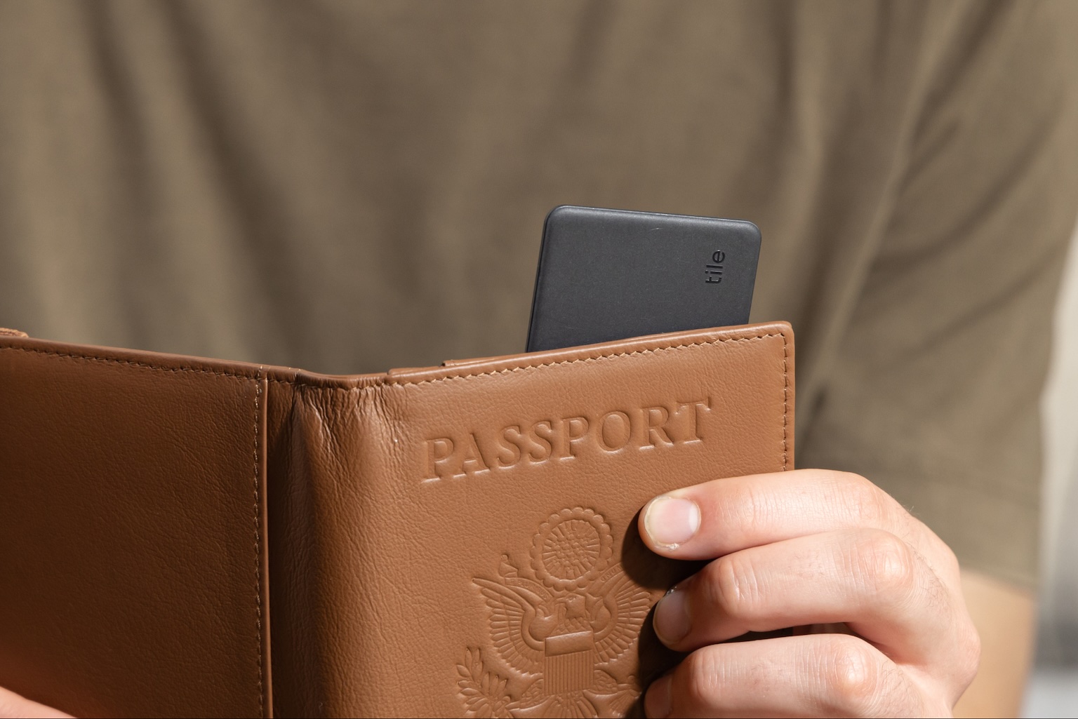 A Tile Slim Black placed inside a leather passport holder.