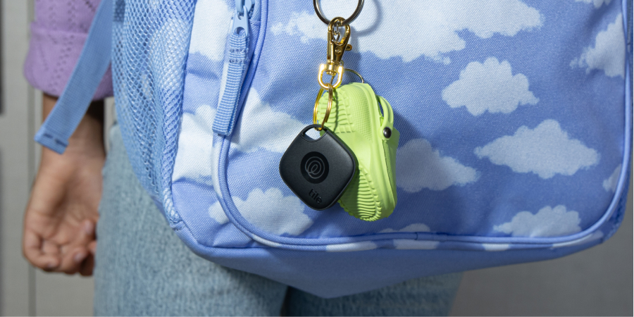 A Tile Mate Black being attached to a child's backpack.