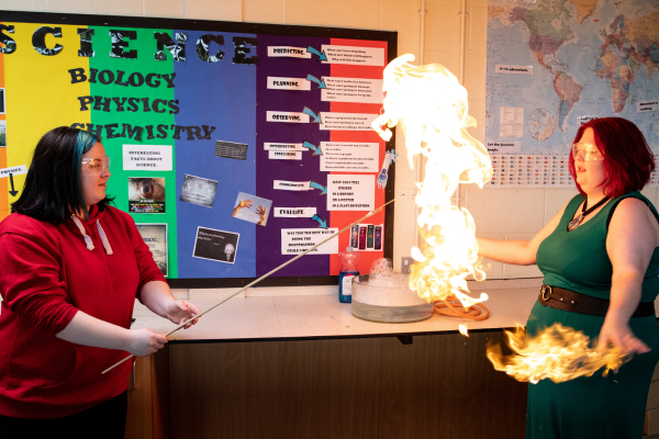 A science teacher stands to the right of the frame and student on the ...